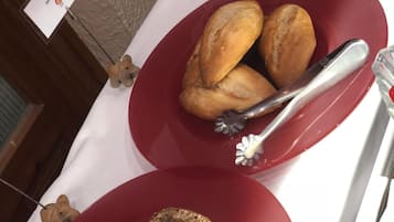 Uma mesa com pratos vermelhos contendo vários pães e uma faca com um garfo.
