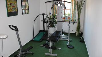Uma academia doméstica com equipamentos de exercício, um banco e uma esteira.