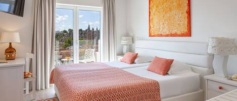 Quarto de hotel com uma cama grande, vista para a cidade e um quadro na parede.