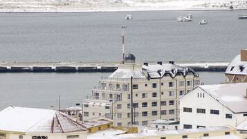 Um edifício costeiro com vários andares, uma torre imponente e um cais com barcos.