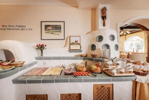 Um buffet de café da manhã com diversos alimentos e uma parede decorativa com um quadro e uma citação.