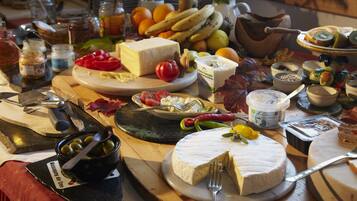 Uma mesa de buffet com diversos queijos, frutas e acompanhamentos.