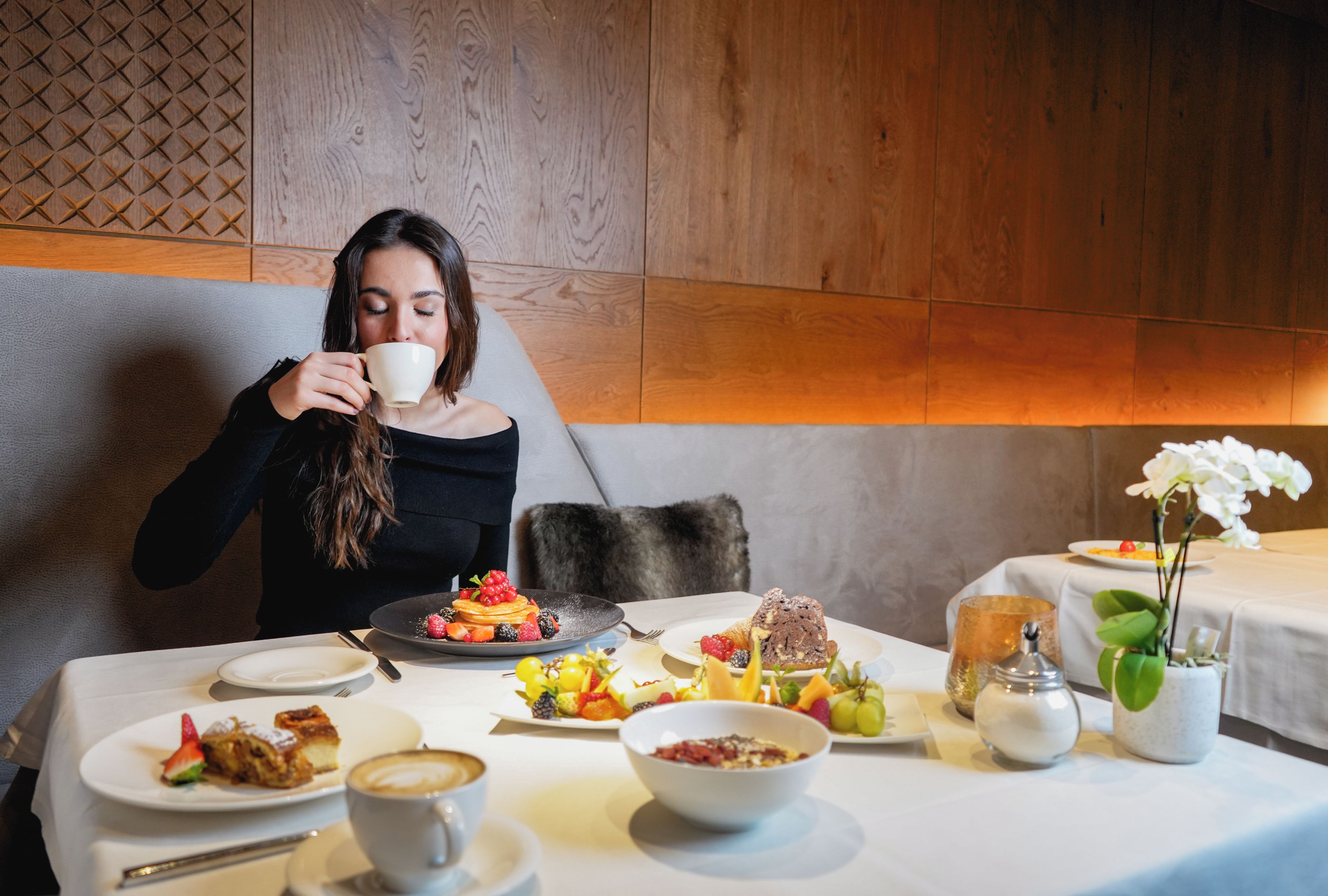 Uma mesa de jantar com diversos pratos, uma xícara de café e um vaso com flores.