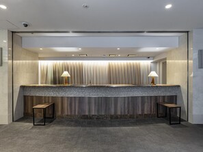 Uma casa de banho moderna com bancada de mármore, duas luzes de parede e um espelho grande.