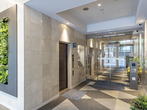Entrada de um hotel moderno com porta de vidro, balcão de recepção e jardim vertical.