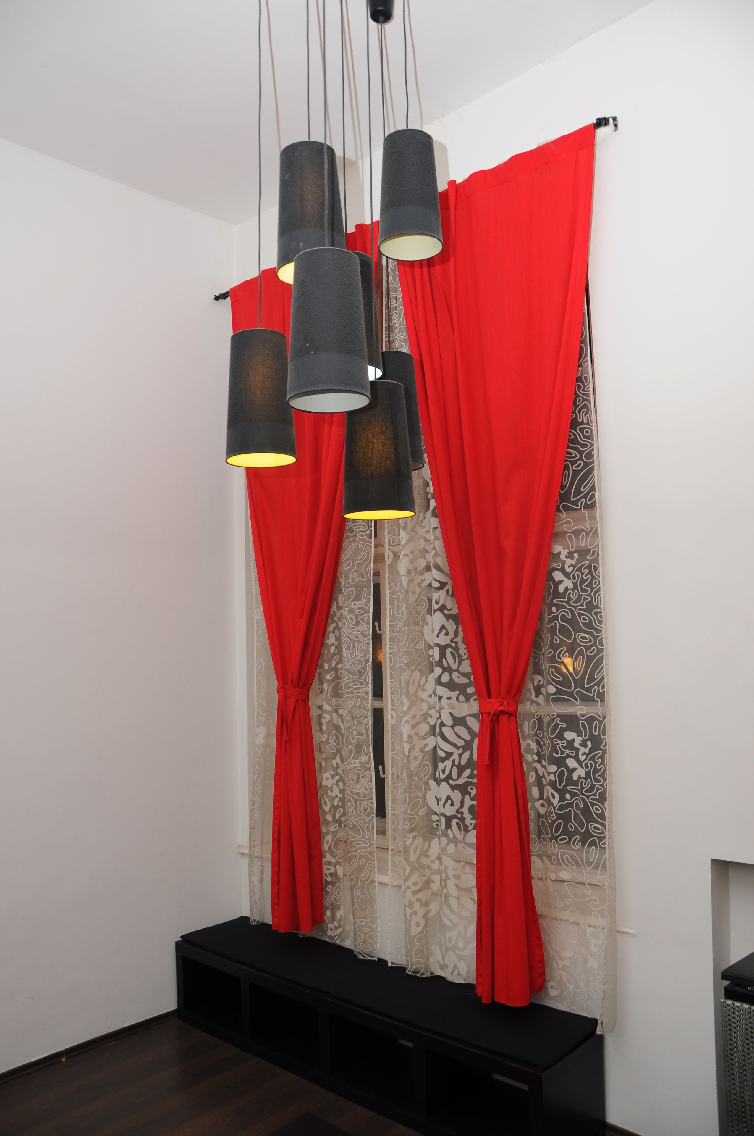 Quarto com um banco preto, cortinas vermelhas e parede estampada.