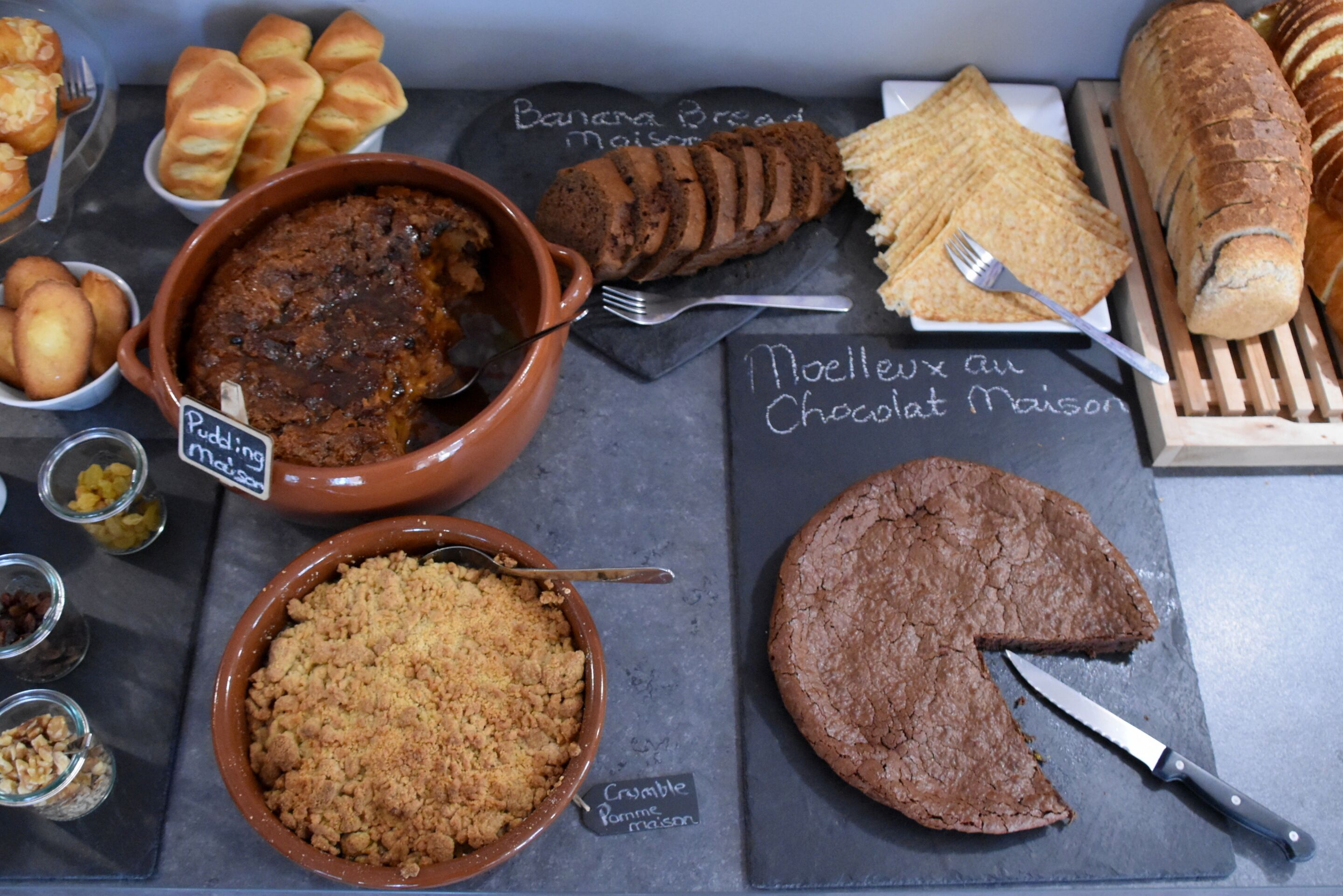 Diversos produtos de panificação, incluindo pão, um bolo de chocolate e um crumble.
