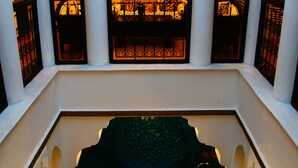 Uma área de piscina interior tranquila, com uma estátua de Buda, colunas brancas e grades elaboradas.