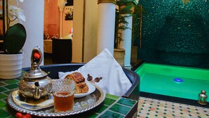 Uma mesa de bilhar com superfície de feltro verde, toalha de mesa branca e uma luminária decorativa.
