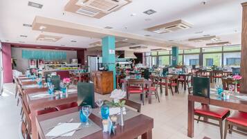 Um restaurante com várias mesas, cadeiras e uma área de cozinha.