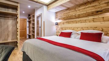 Quarto com cabeceira de madeira, cama com roupa de cama branca e vermelha, e guarda-roupa embutido.