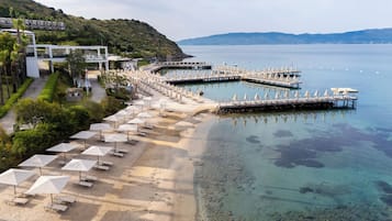 Resort à beira-mar com guarda-sóis, espreguiçadeiras, um píer e águas azul-claras.