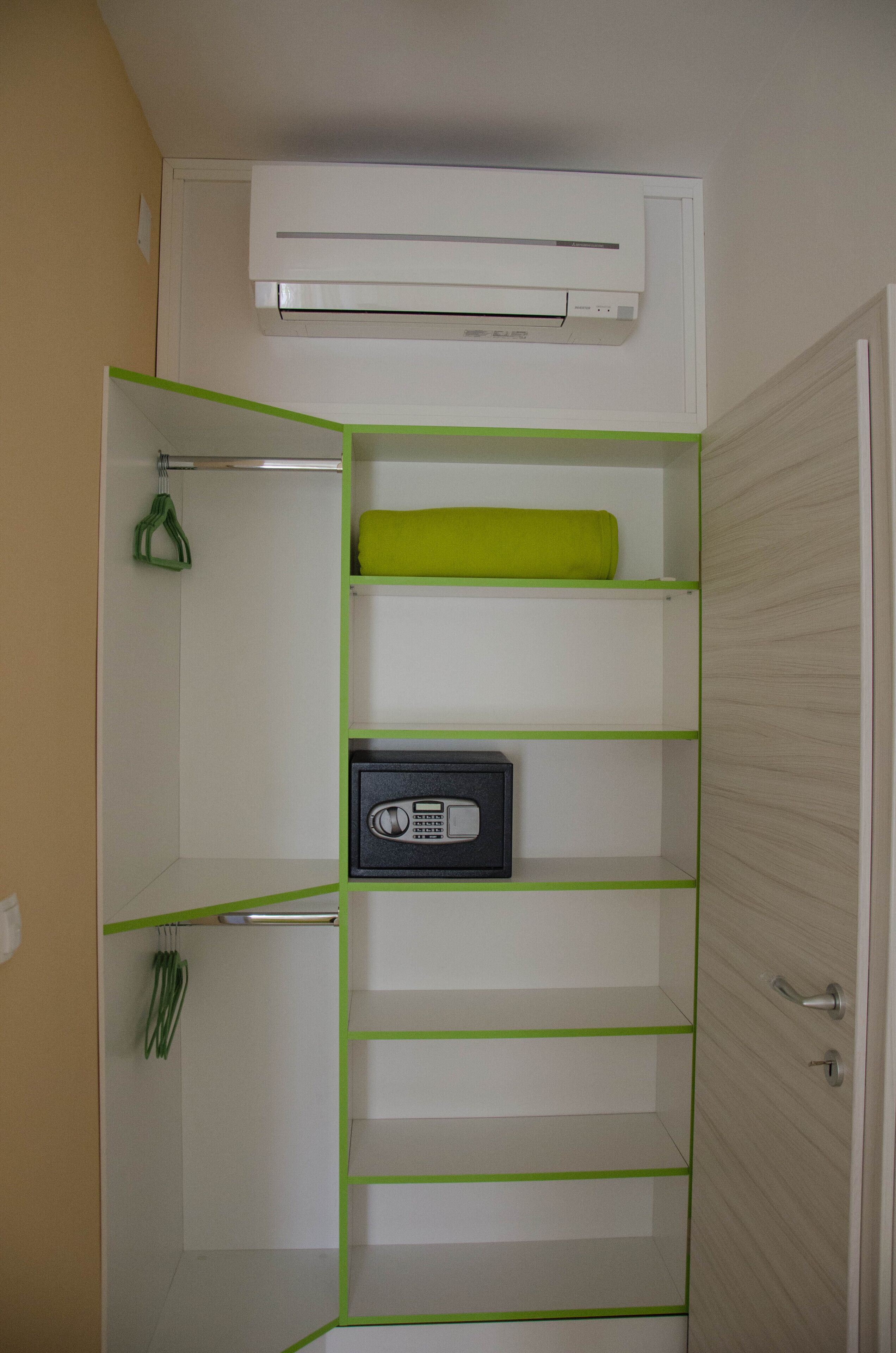 Um closet amplo com várias prateleiras, uma toalha verde e um aparelho de ar condicionado acima.