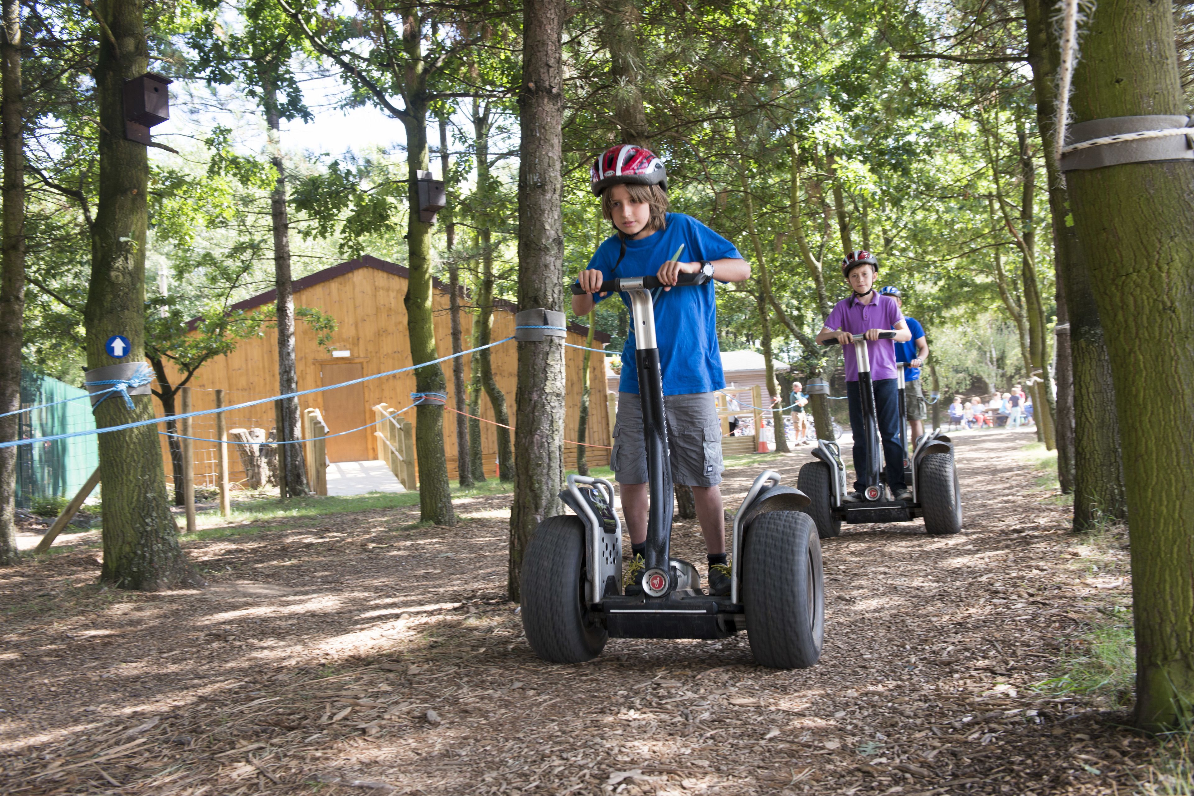 Uma pessoa andando em um Segway por uma trilha de terra cercada por árvores.
