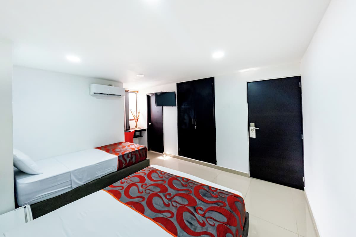Quarto de hotel com cama, escrivaninha, cadeira, guarda-roupa e televisão.