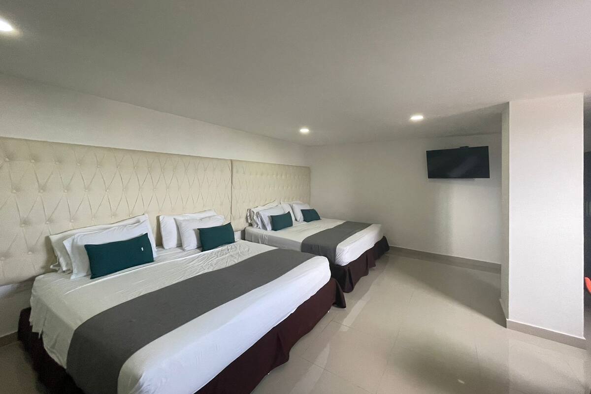 Quarto de hotel com duas camas, uma televisão na parede e uma TV de tela plana montada sobre a cama.