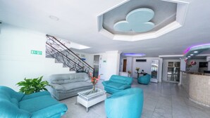 Um lobby moderno com escada, área de estar, balcão de recepção e máquina de vendas.