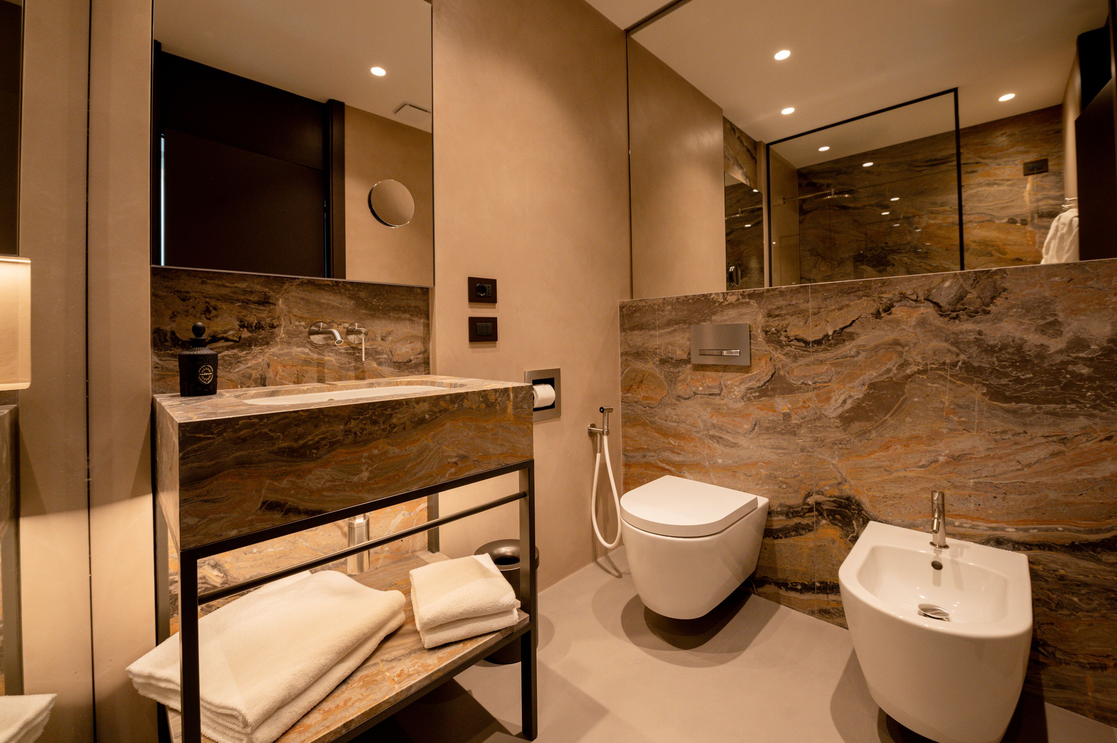 Uma casa de banho moderna com lavatório de mármore, um bidé e um espelho.