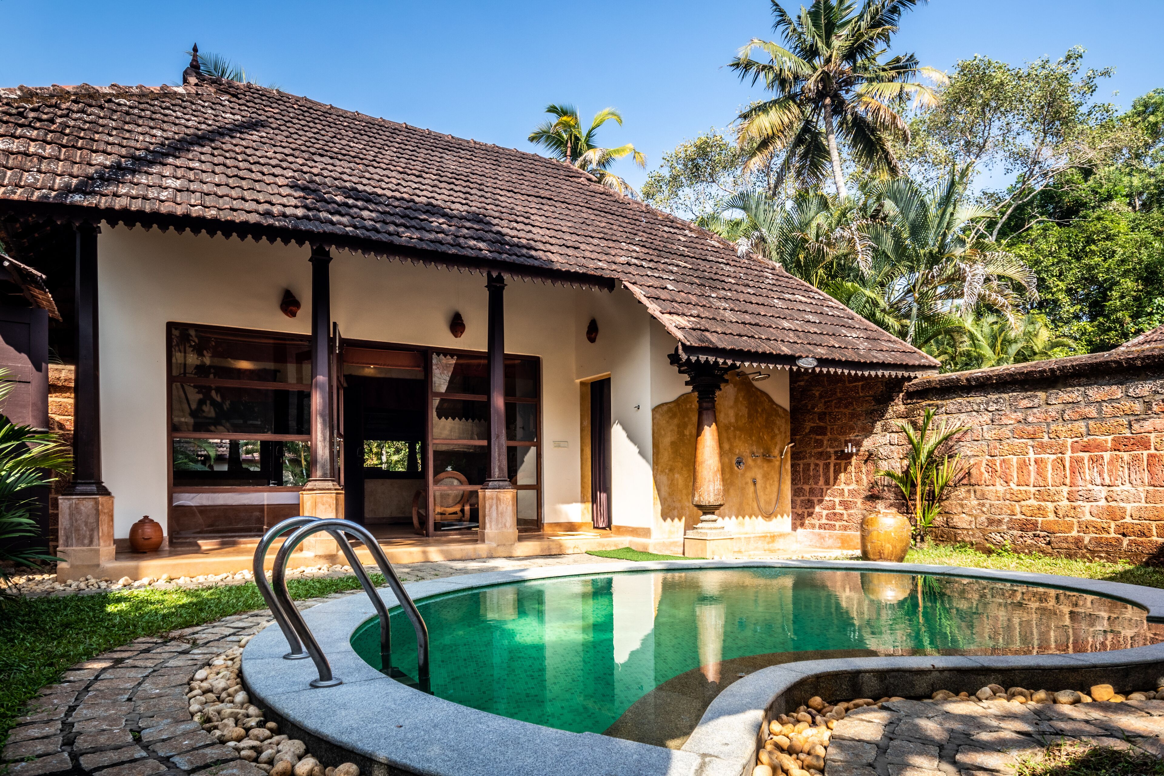 Uma casa com piscina, telhado cerâmico e muro de tijolos.