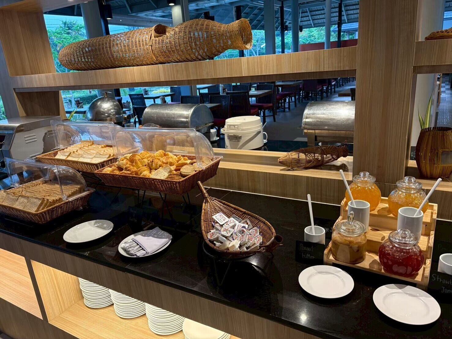 Uma área de buffet com diversos alimentos, incluindo pães, doces e bebidas.