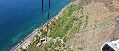 Um teleférico com paisagem montanhosa e costa marítima.