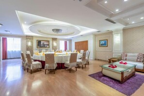 Uma sala de jantar espaçosa com mesa redonda, várias cadeiras e uma televisão.