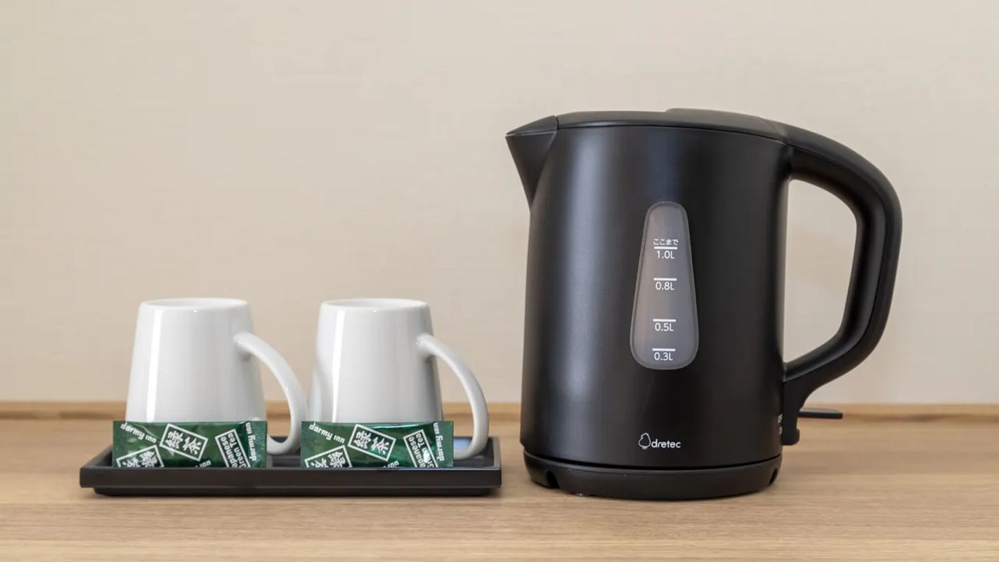 Bule elétrico preto com visor digital e bandeja com duas chávenas brancas e saquetas de chá verde.