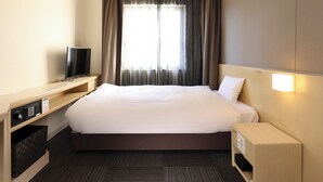 Quarto de hotel com uma cama grande, uma TV sobre um suporte de madeira, uma mesinha de cabeceira e uma janela com cortinas.