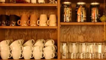 Uma cozinha com prateleiras cheias de garrafas de vinho, canecas de café e copos.
