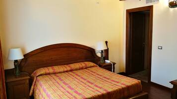 Quarto com cama de madeira, duas luminárias de cabeceira, mesa de cabeceira e uma porta.
