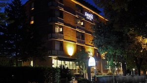 Um hotel com vários andares, um letreiro chamativo, varandas e uma fachada bem iluminada.