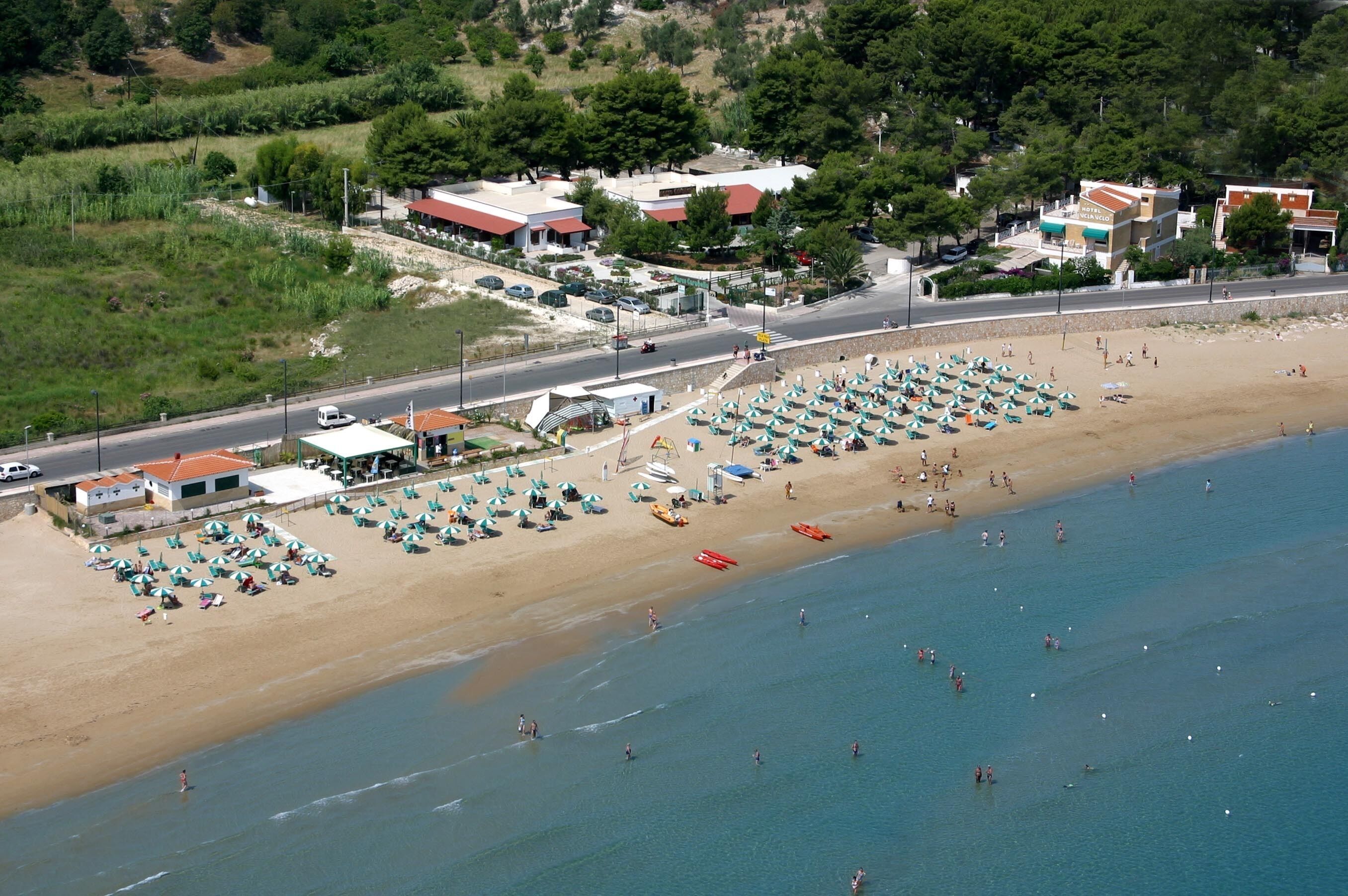 Vista aérea de uma praia com vários guarda-sóis e pessoas.