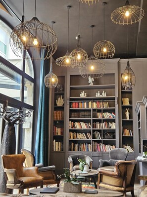 Um espaço aconchegante para leitura, com poltronas de couro, uma mesa de centro e uma estante repleta de livros.
