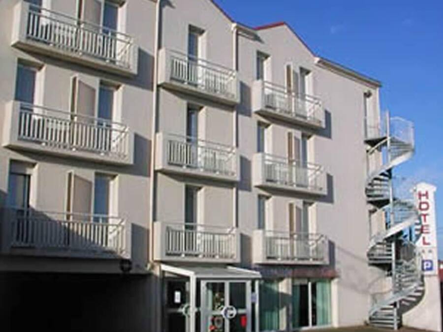 Um hotel com vários andares, varandas, uma entrada visível e uma escadaria em espiral.