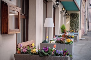 Uma fileira de vasos de vime com flores coloridas e objetos decorativos na fachada de um edifício.