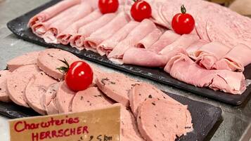 Exposição de frios e charcutaria, com uma placa indicando 'Charcuteries HERRSCHER' e um indicador de distância 'a 2,5 km'.