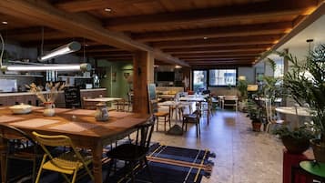 Uma sala de jantar ampla com uma longa mesa de madeira, diversas cadeiras e teto rústico.