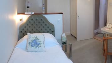 Quarto com cama, mesa de cabeceira com uma garrafa, espelho e porta para o banheiro.