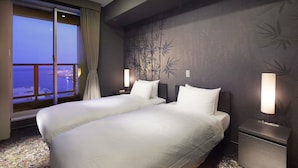 Quarto de hotel com duas camas, uma janela grande com vista e parede com padrão de bambu.