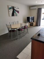 Uma sala de estar moderna com área de jantar, televisão de tela plana e ar condicionado.