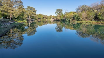 Um rio tranquilo refletindo árvores e um céu limpo.
