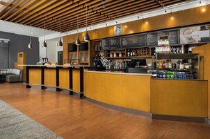 Uma área de bar moderna com teto de madeira, um quadro de cardápio e um balcão com diversas bebidas.