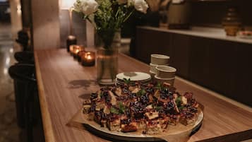 Uma mesa de madeira com um prato de sobremesas, velas e um vaso de flores.