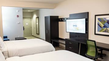 Quarto de hotel com duas camas, uma mesa de escritório, uma cadeira, uma televisão e uma porta que dá para outro quarto.