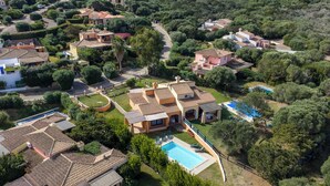 Vista aérea de um bairro residencial com casas, piscina e uma estrada sinuosa.