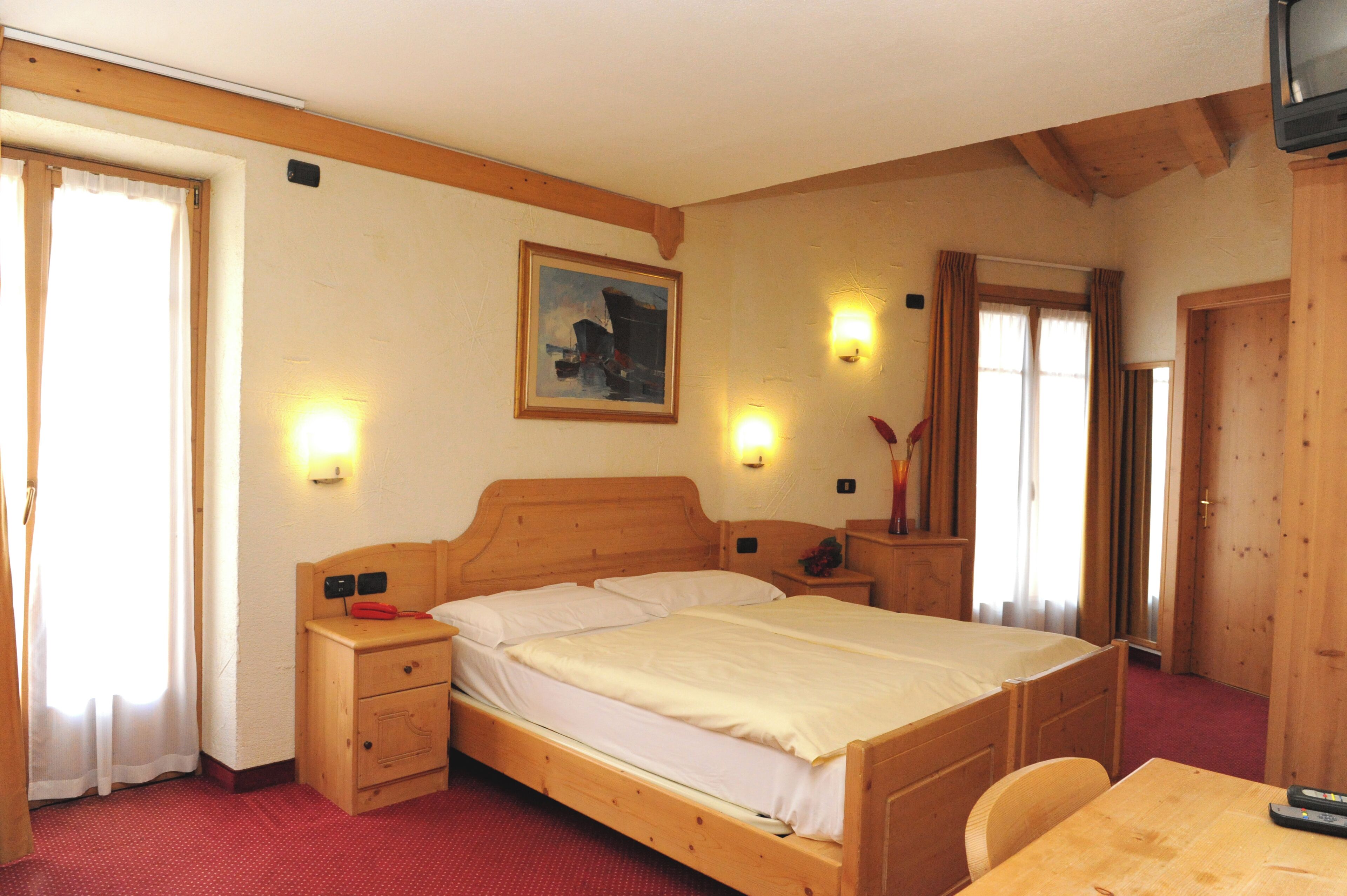 Uma cama de madeira num quarto com tapete vermelho, paredes de madeira e um quadro na parede.