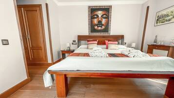 Quarto com cama de madeira, mesa de cabeceira, quadro na parede e uma porta.