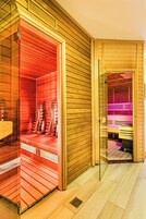 Sala de sauna com paredes de madeira e porta de vidro, um banco e um banco com toalha.