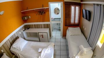 Quarto de hotel com duas camas, uma kitchenette pequena, banheiro com espelho e televisão.