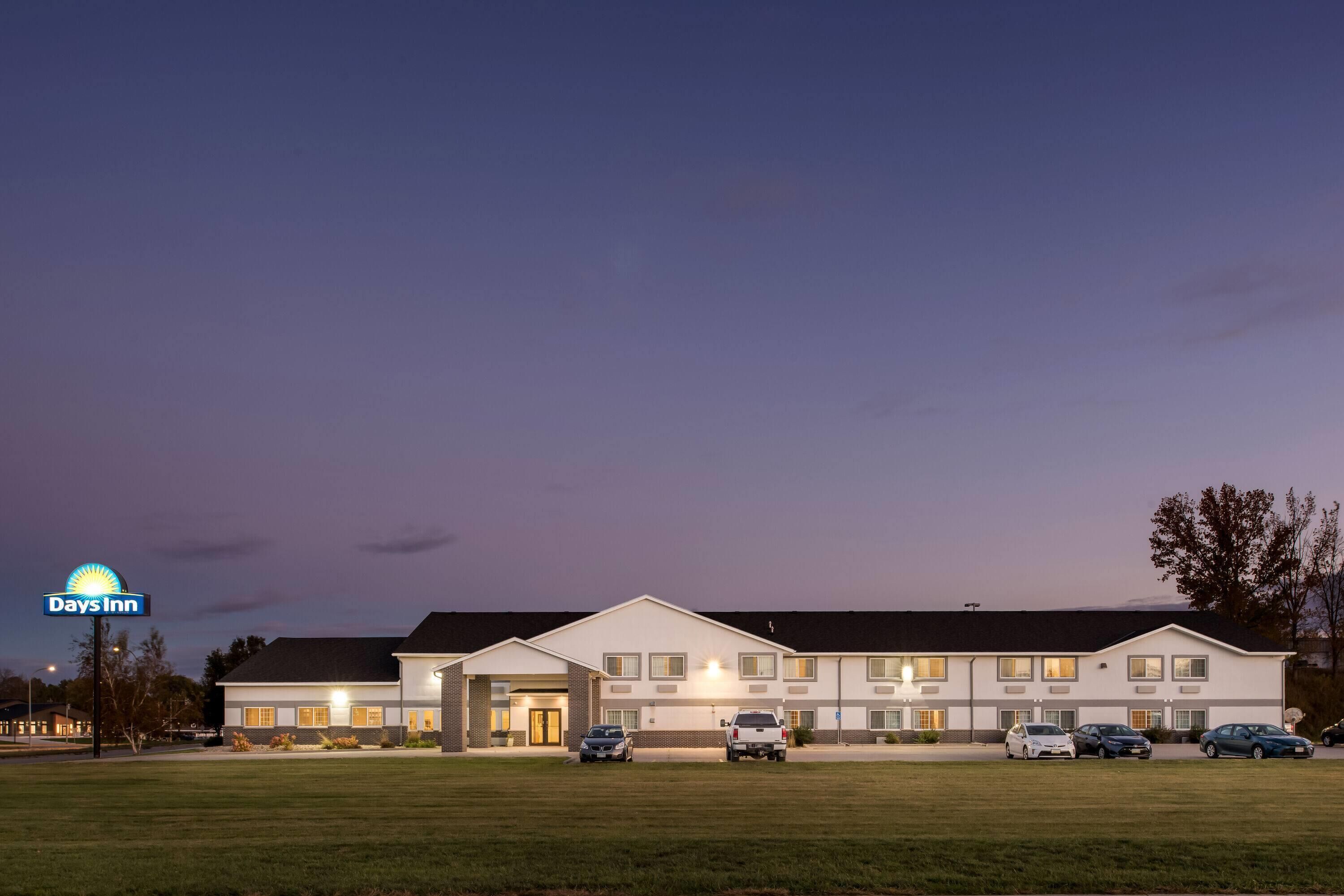 Um hotel Days Inn com estrutura em dois andares, estacionamento e entrada bem iluminada.